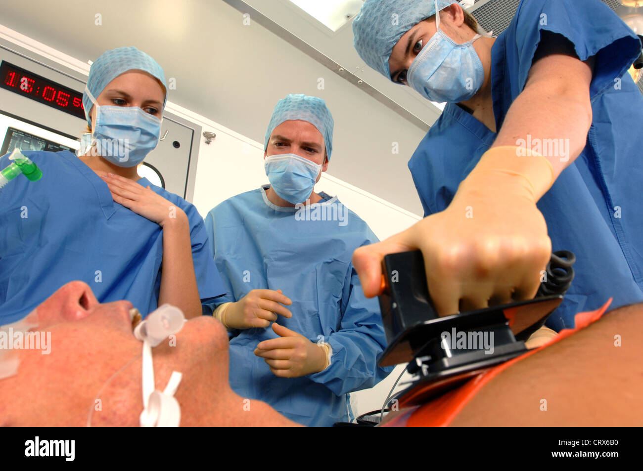 Doctors using a defibrillator to resuscitate a male heart attack victim ...