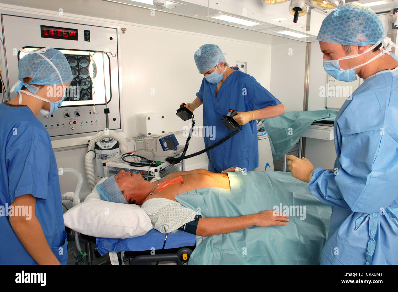 Doctors using a defibrillator to resuscitate a male heart attack victim ...