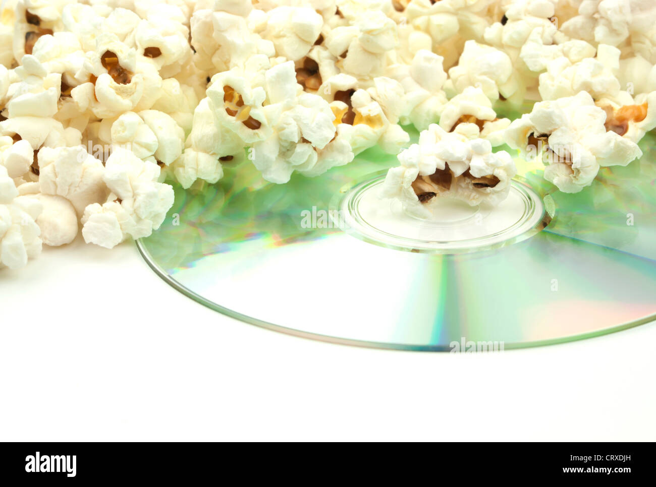 White fluffy tasty popcorn spilling over a shiny dvd movie disc ...