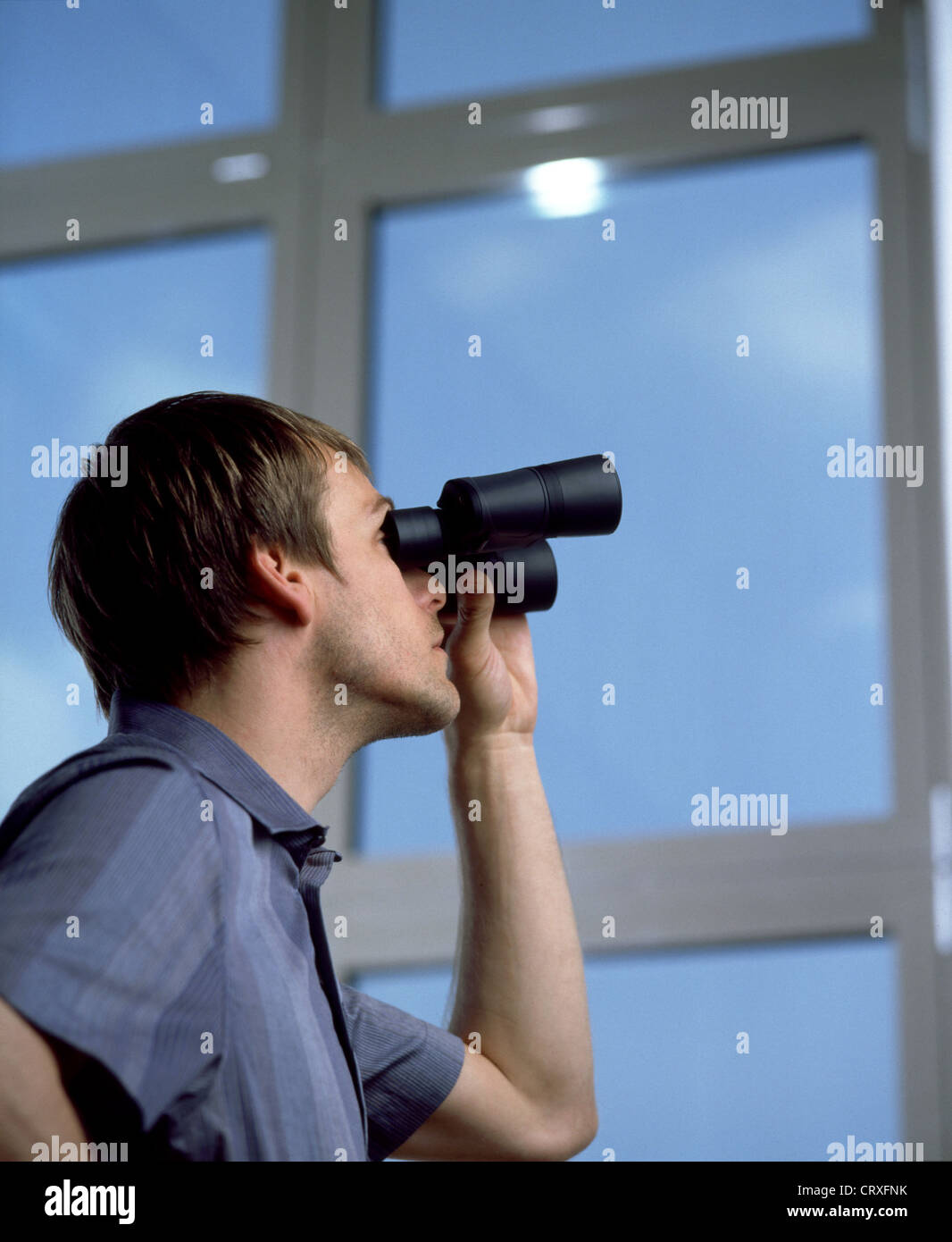 A man looks through binoculars from the window Stock Photo - Alamy