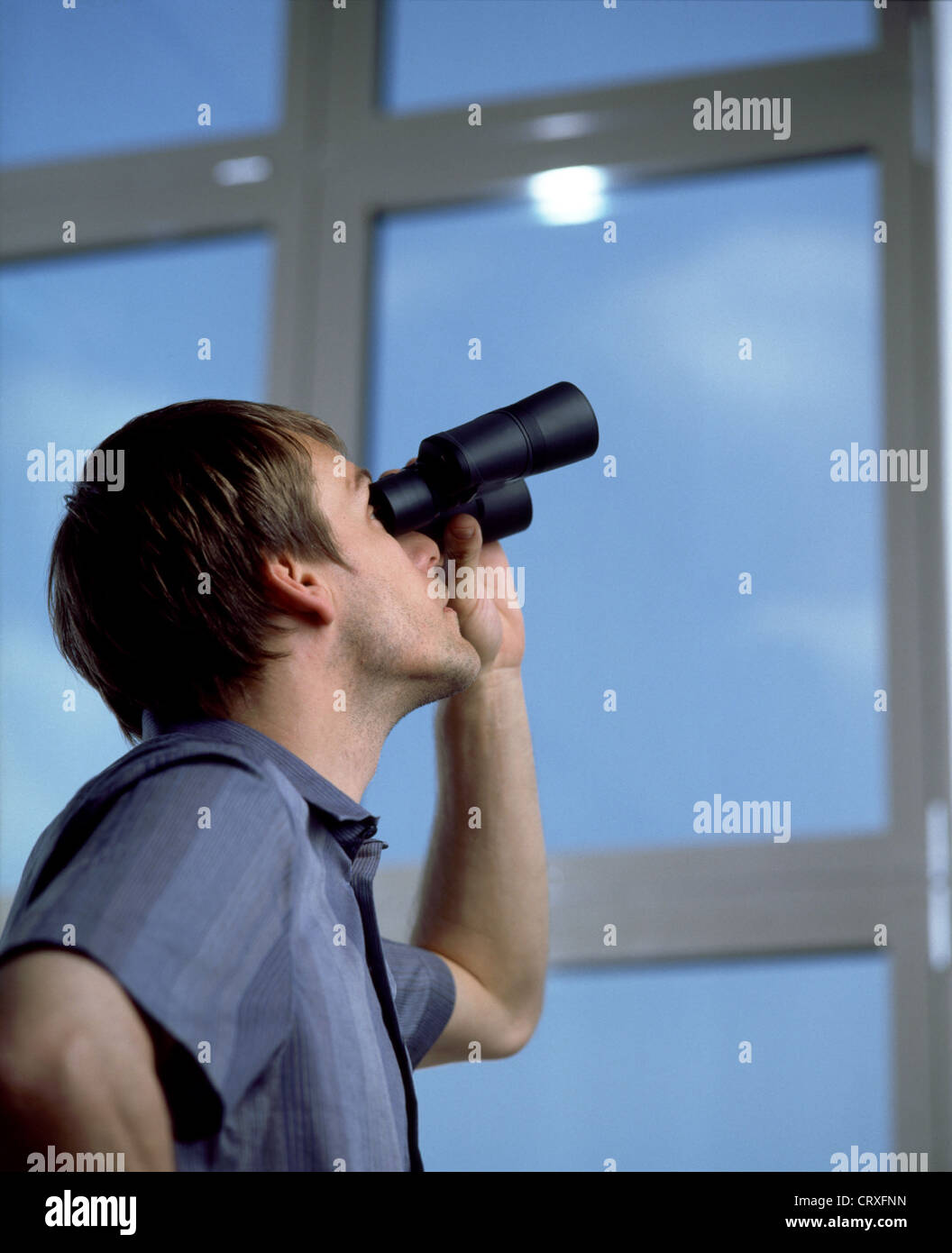 A man looks through binoculars from the window Stock Photo - Alamy