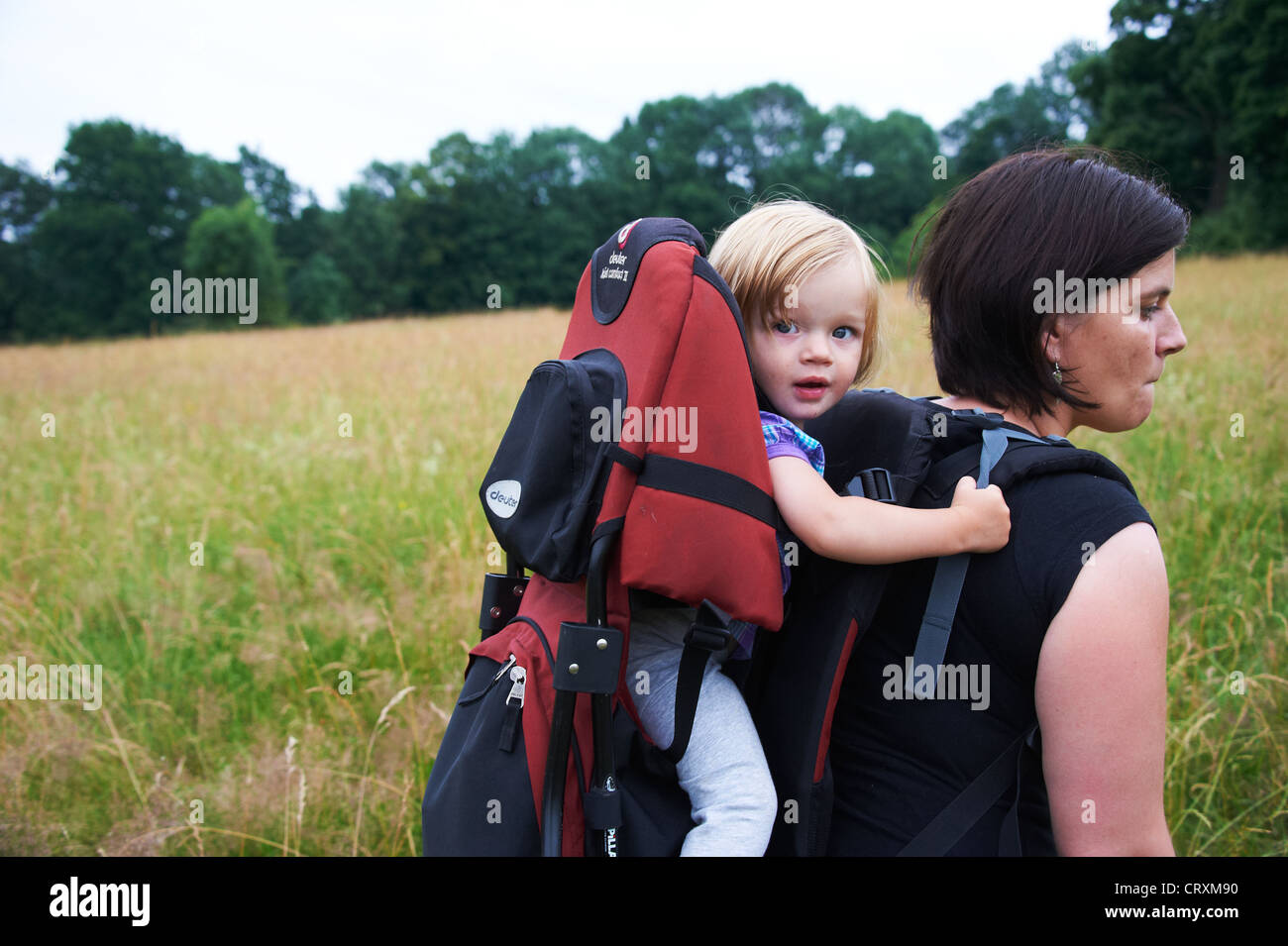 A woman mother carries her child in a backpack outdoor Stock Photo - Alamy