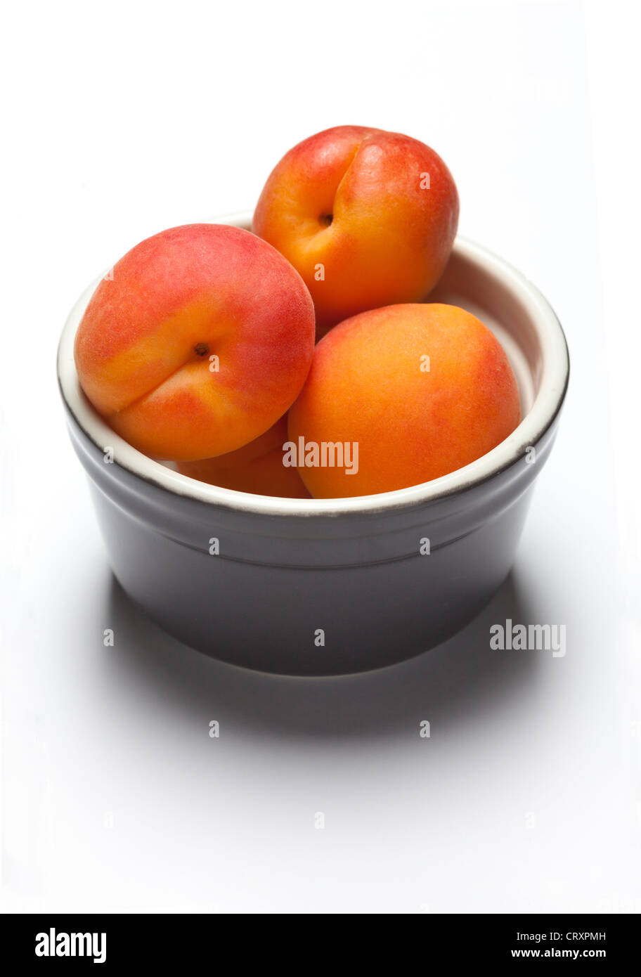 Three Apricots in dish on a light background Stock Photo - Alamy