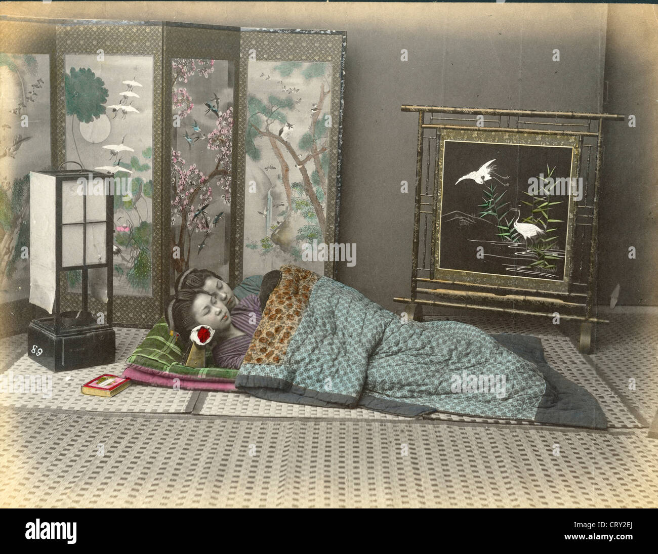 Colorized photo of two women sleeping on a futon and covered in a quilt ...