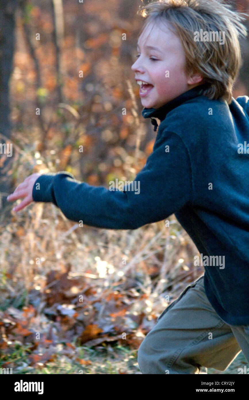 Boy age 9 running in backyard field playing a touch football game ...