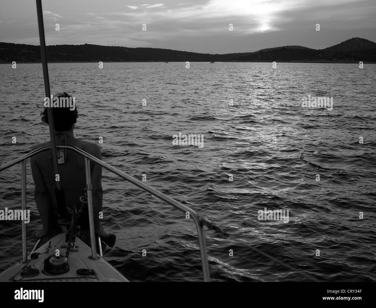 A girl in front of the sailing boat pulpit at sunset - black and white ...