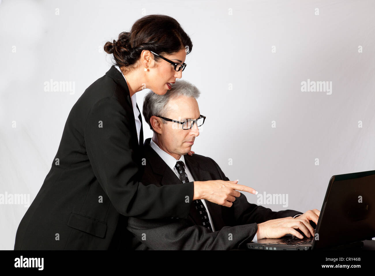 Business woman standing over her male counterpart as she corrects his ...