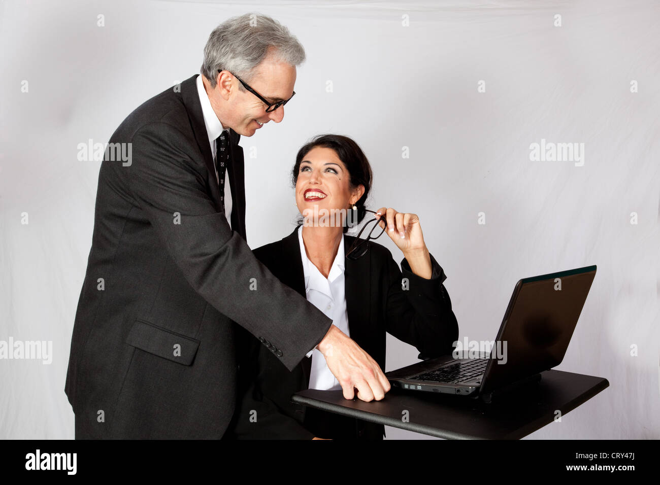 Business man standing over his female counterpart as she corrects her ...