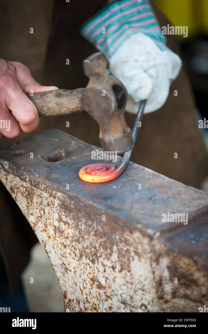 Blacksmith making decorative iron work using hammer and anvil Stock ...
