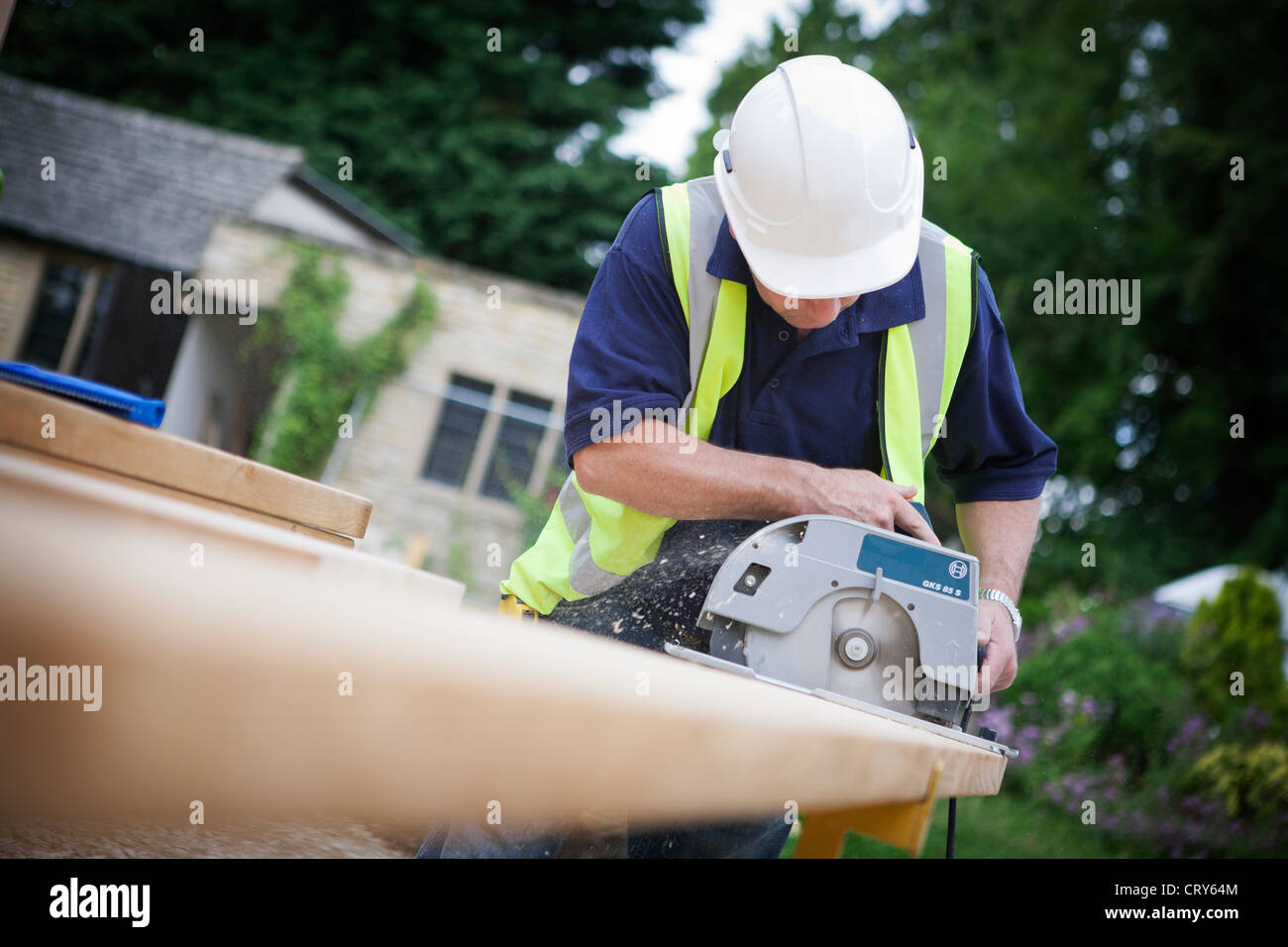 Builder using a circular saw to cut rafters to size on a building site ...