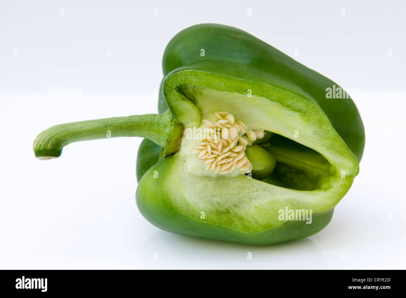 Close up of green pepper with piece cut on against a white background ...