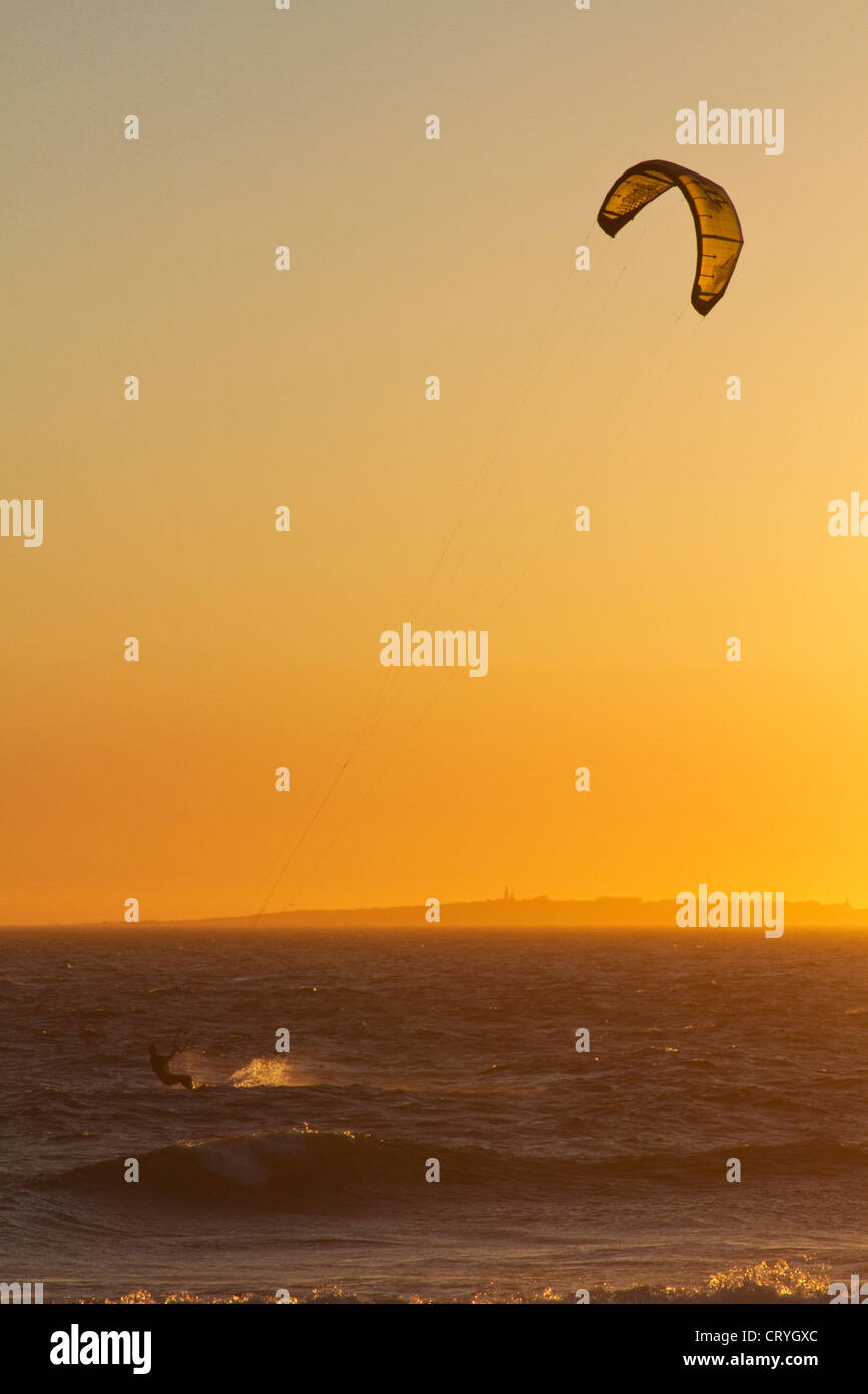 Kite surfer at sunset with Robben Island just visible on the horizon ...