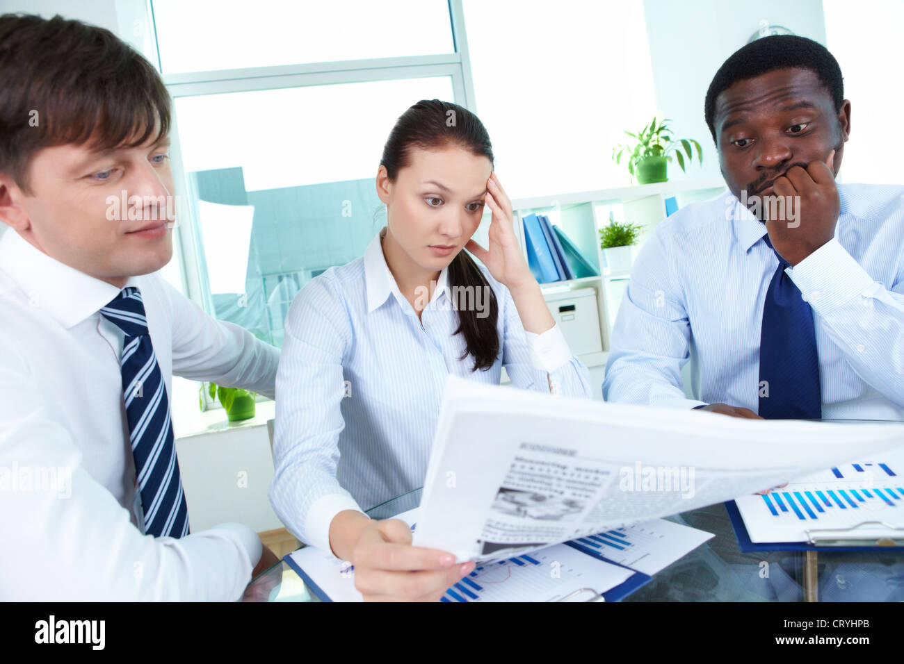 Three bored colleagues reading newspaper at meeting Stock Photo - Alamy