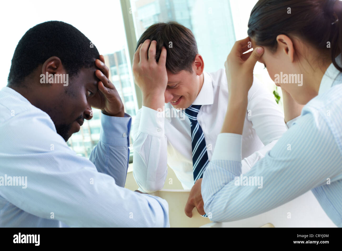 Portrait of three business partners touching their heads while thinking ...