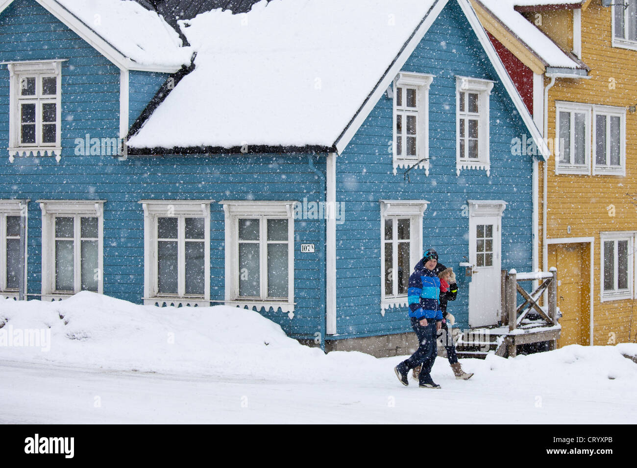 Couple walk past traditional wooden buildings on Storgata in the quaint ...