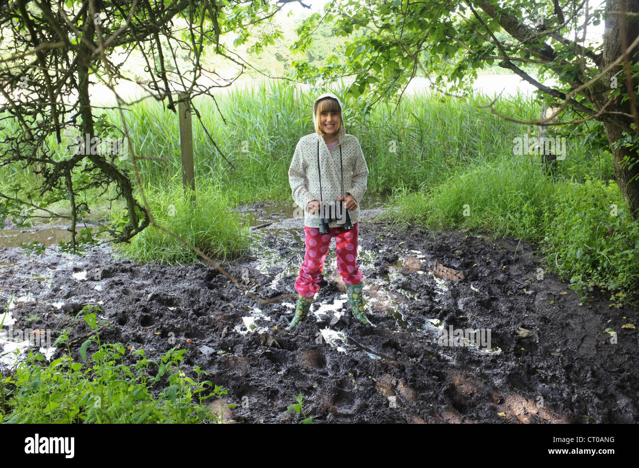 A young girl with binoculars wades through mud Stock Photo - Alamy