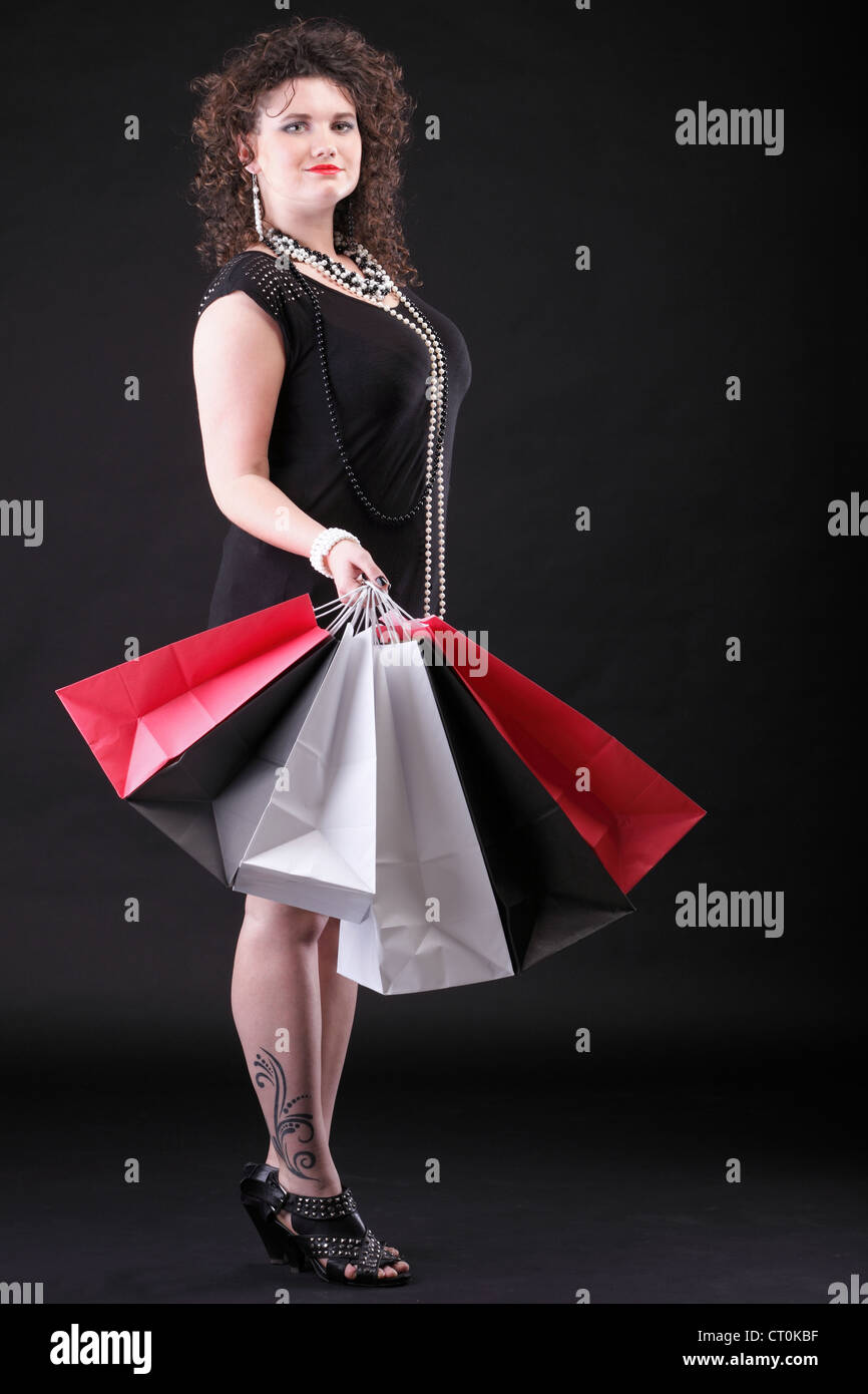 lovely curver woman with shopping bags over black background Stock ...