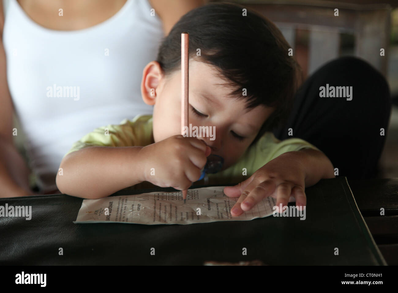 It's a photo of a young Chinese boy baby who try to write with a pen on ...