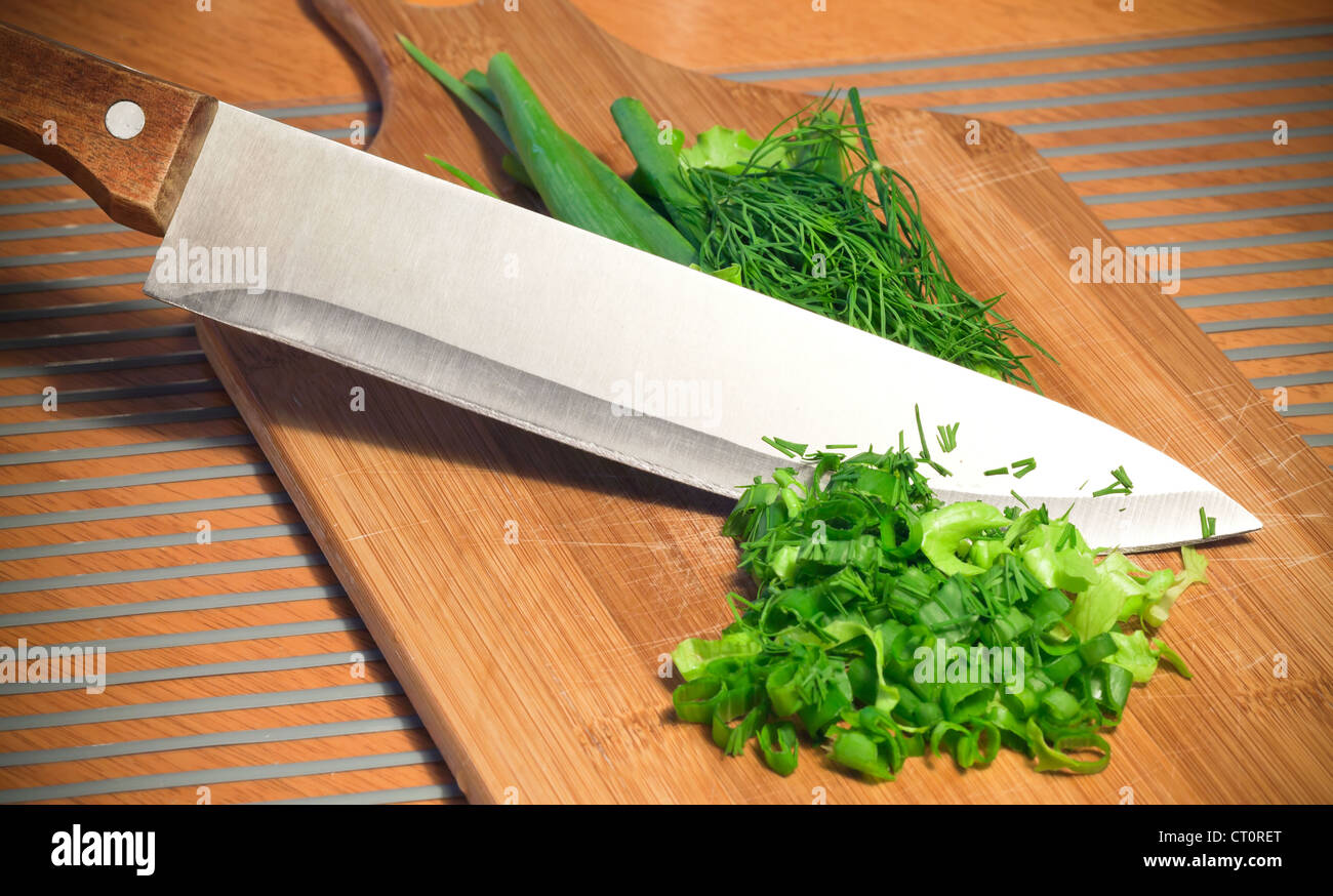 Sliced greens with knife on wooden cutting board Stock Photo - Alamy