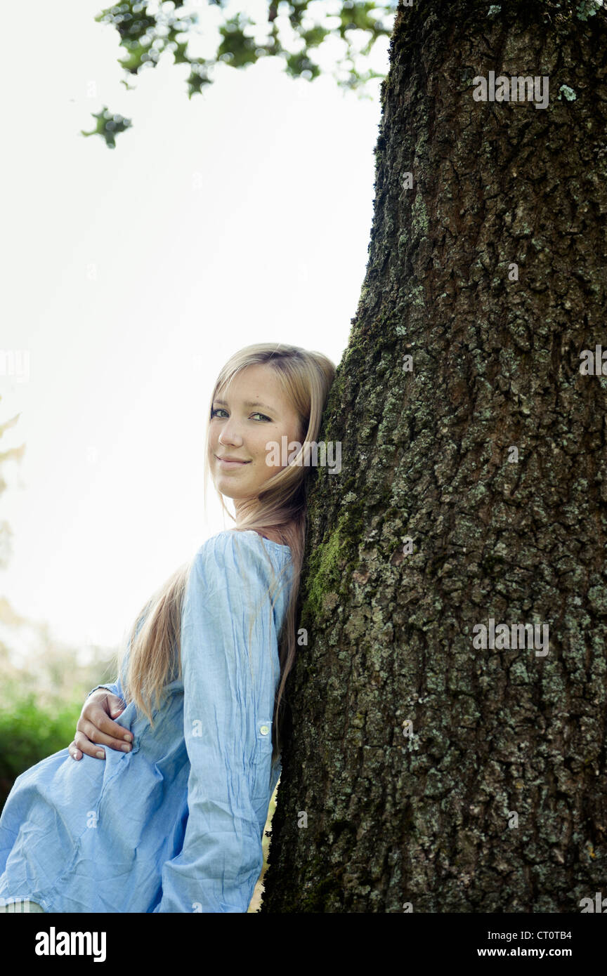 Woman leaning against tree outdoors Stock Photo - Alamy