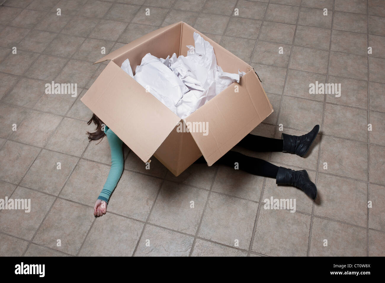 Teenage girl lying under cardboard box Stock Photo - Alamy