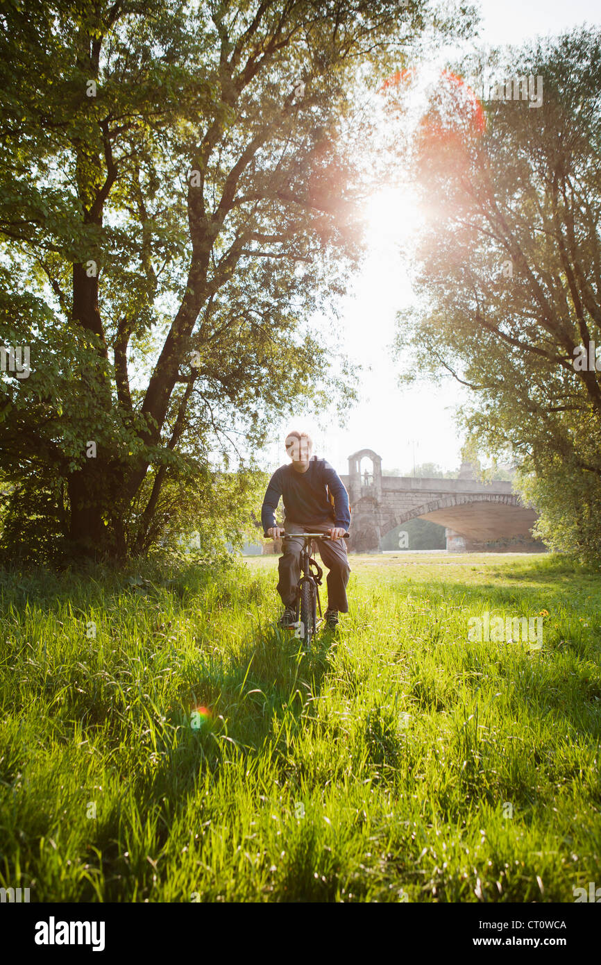 Man riding bicycle in field Stock Photo - Alamy