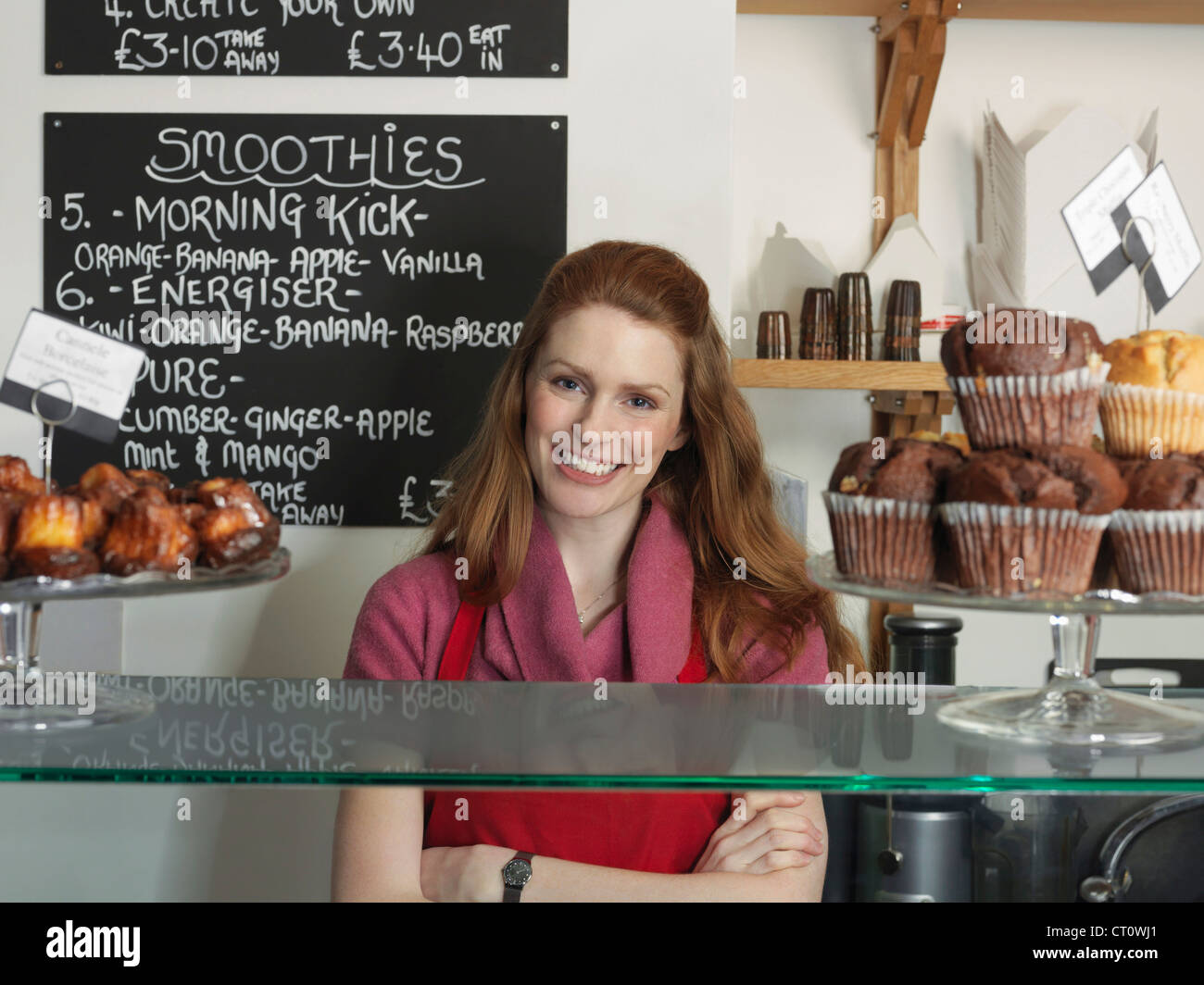 Server smiling behind bakery counter Stock Photo - Alamy