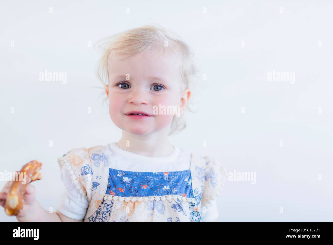Toddler girl eating pastry indoors Stock Photo - Alamy