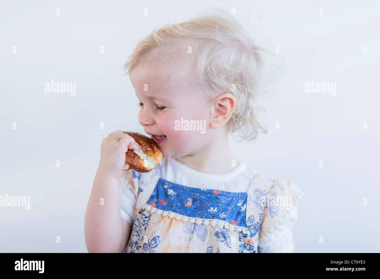 Toddler girl eating pastry indoors Stock Photo - Alamy