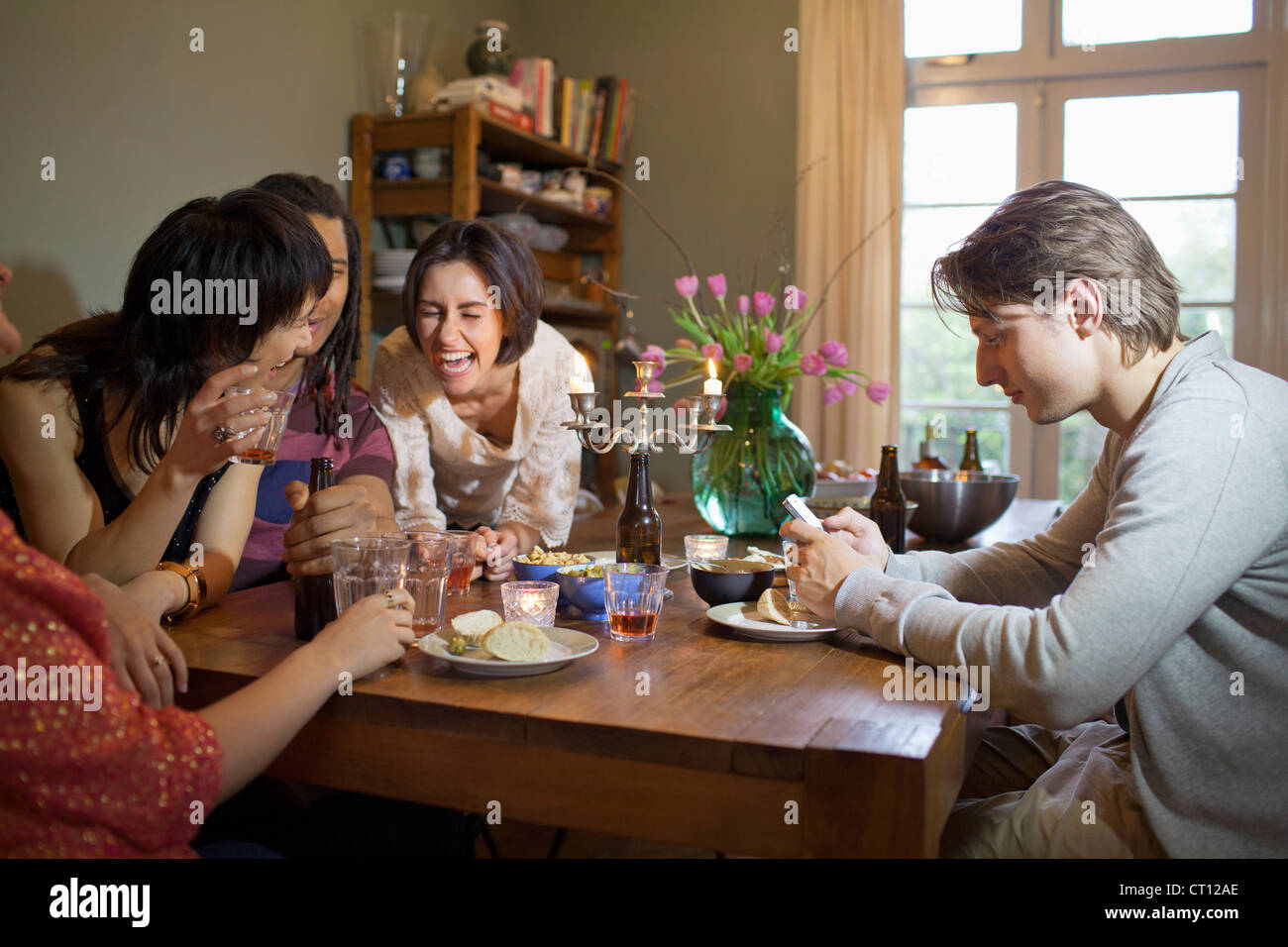 Friends laughing at dinner table Stock Photo - Alamy
