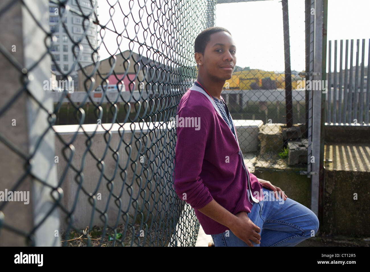 Smiling man leaning against fence Stock Photo - Alamy
