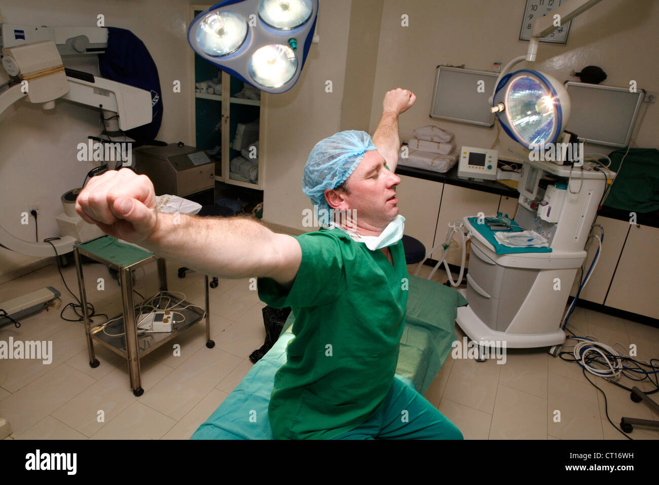 An over-worked Surgeon stretches his arms out as he rests on the ...