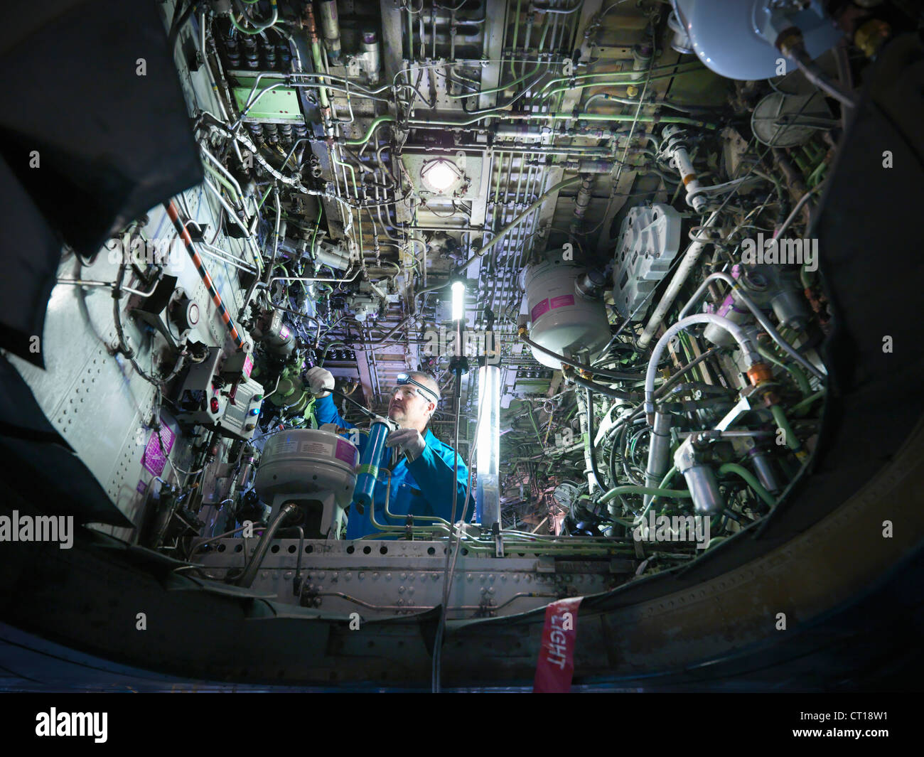 Worker adjusting airplane machinery Stock Photo - Alamy
