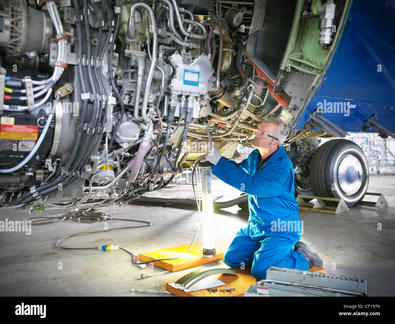 Worker examining airplane machinery Stock Photo - Alamy