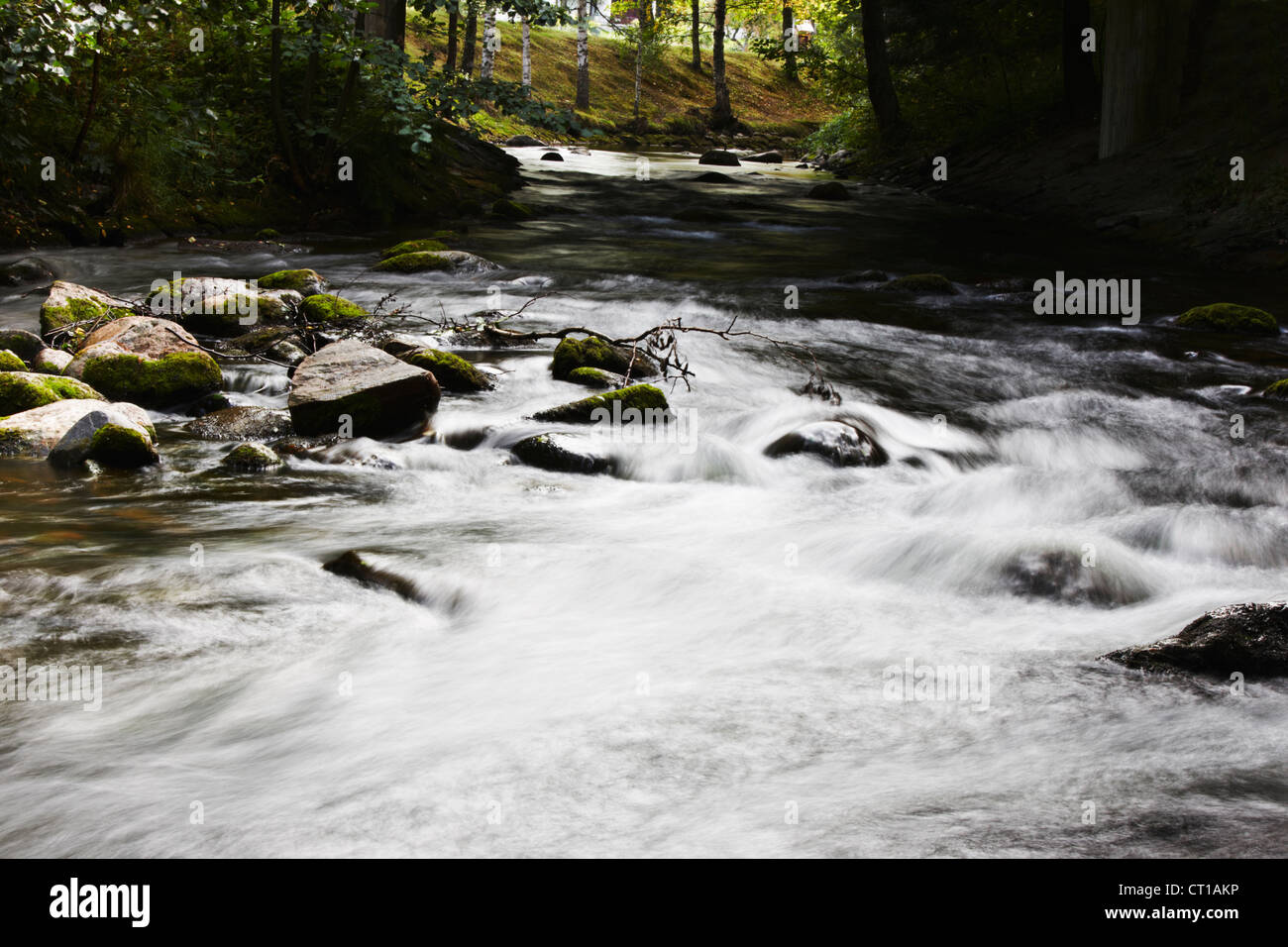 Blurred view of river rushing over rocks Stock Photo - Alamy
