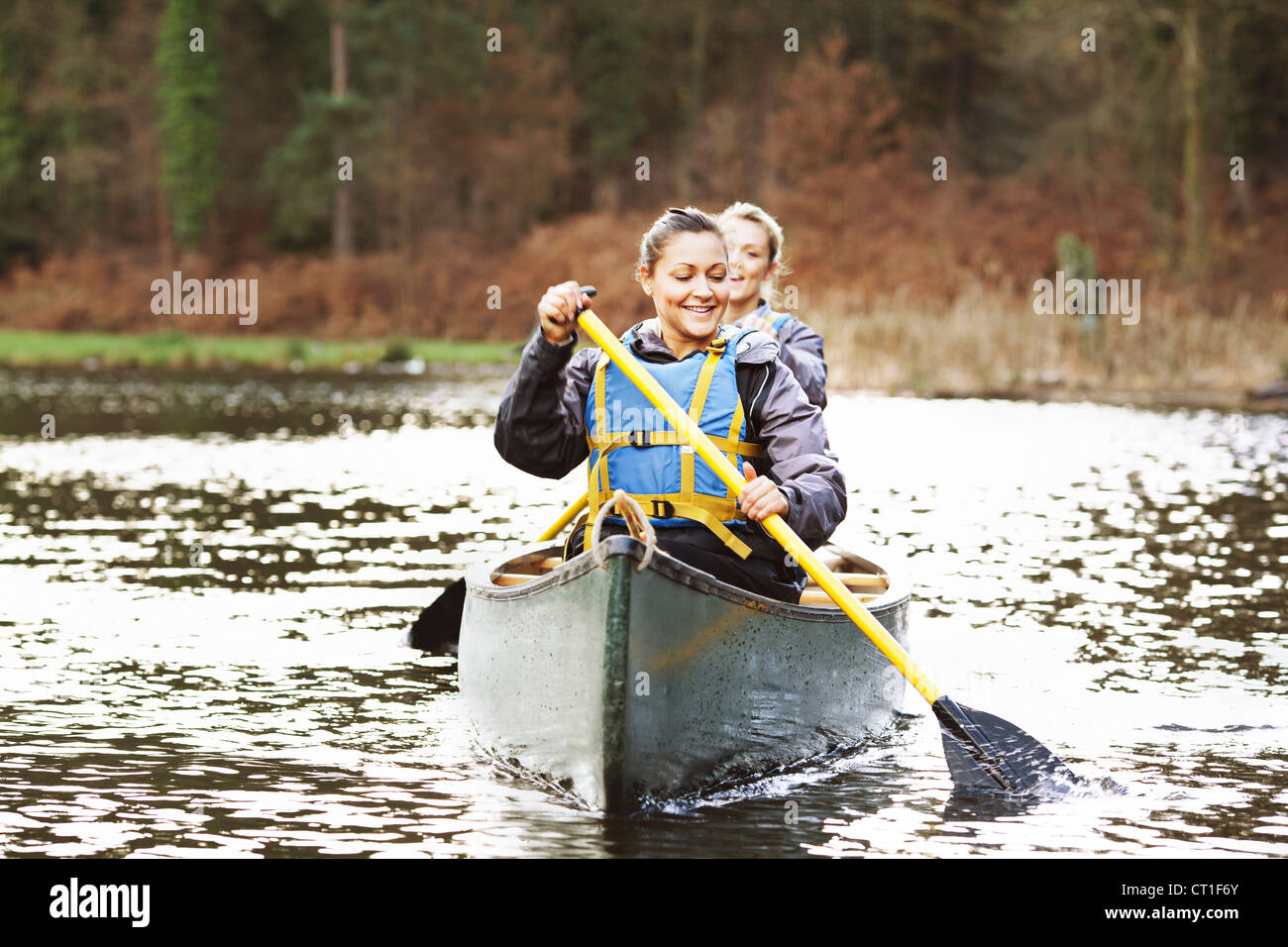 Women rowing canoe on still lake Stock Photo - Alamy