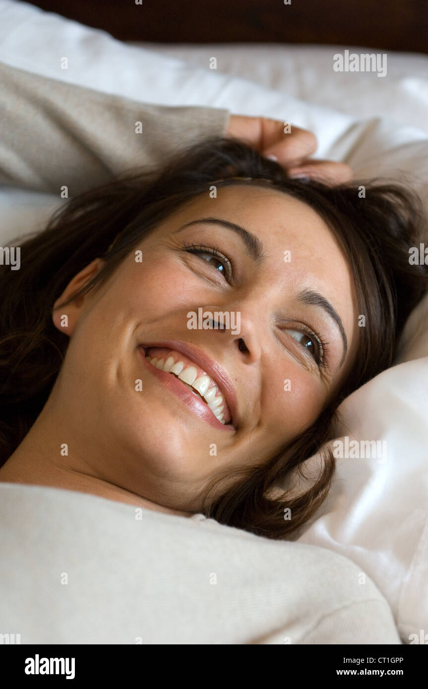 Smiling woman laying in bed Stock Photo - Alamy