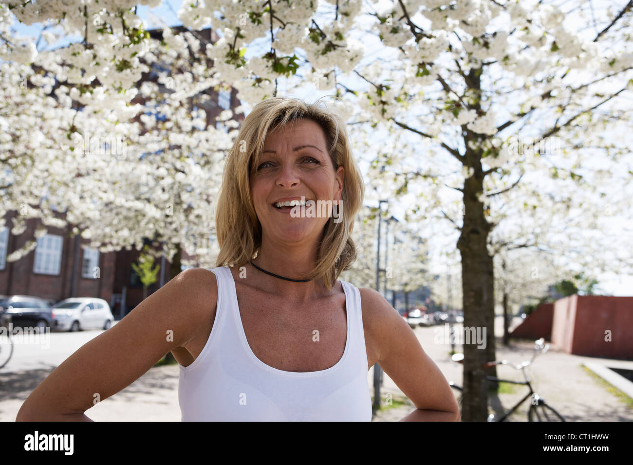 Smiling woman standing under tree Stock Photo - Alamy