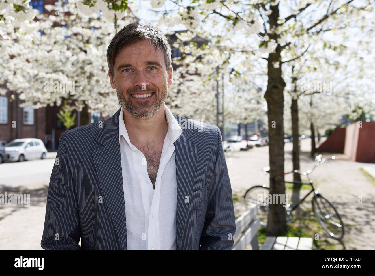 Smiling man standing under tree Stock Photo - Alamy