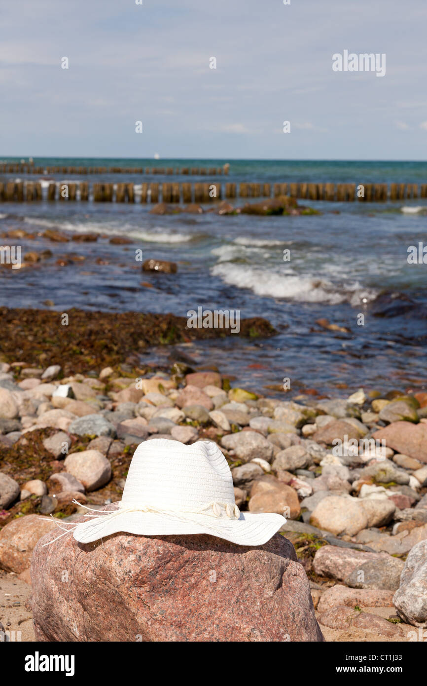 An white straw hat lies on a red big rock on the beach Stock Photo - Alamy