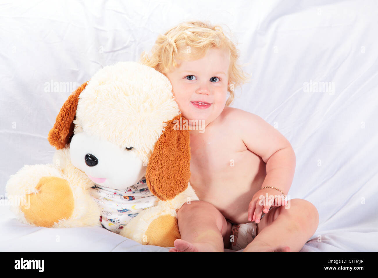 cute young child baby with cuddly dog toy in nappy on white background ...