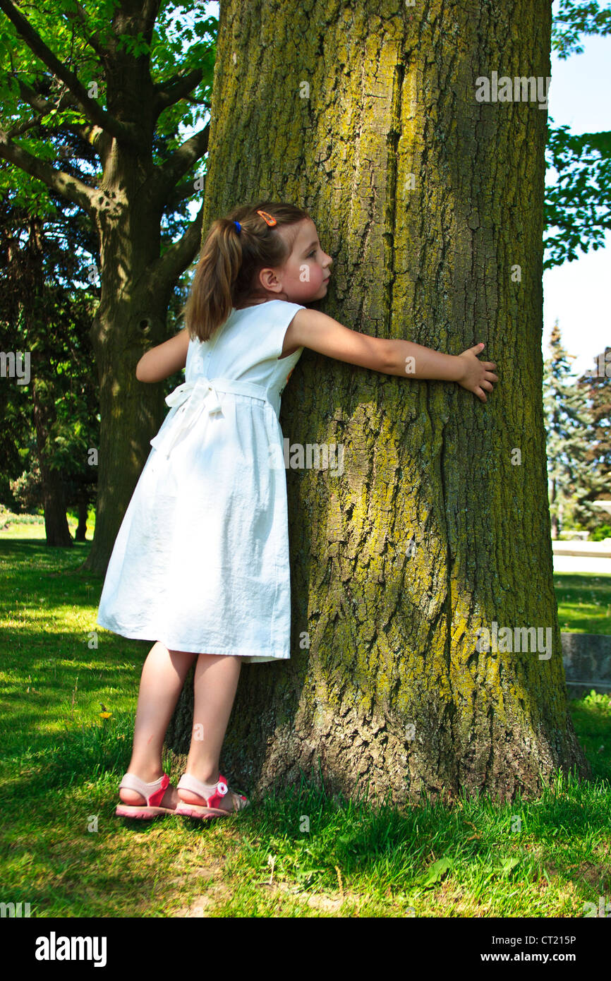 Four year old little girl hugging tree Stock Photo - Alamy
