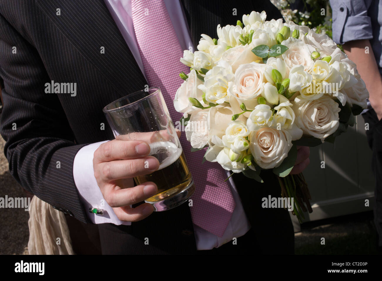 Wedding relative holds bridal bouquet and glass of pims after a civil ...