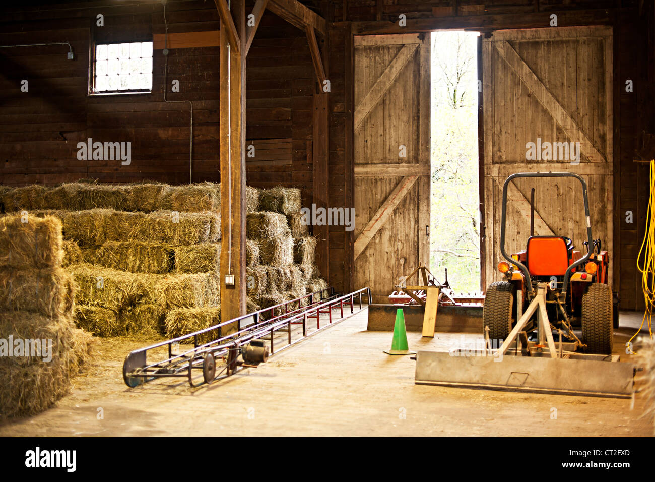 Interior of wooden barn with hay bales stacks and farm equipment Stock ...
