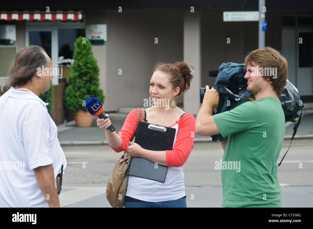 Tv team male cameraman female reporter interview on street hi-res stock photography and images ...