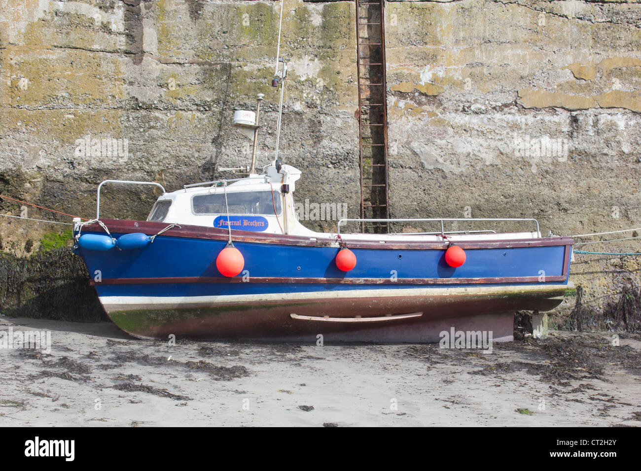 Seahouses Harbour with a fishing boat at low tide Stock Photo - Alamy