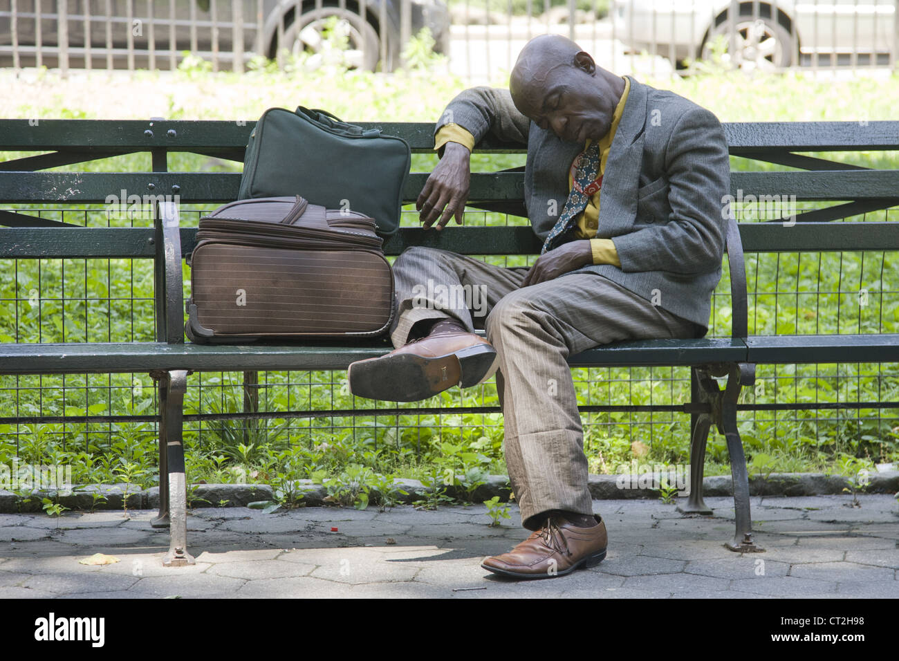 Tired man with his belongings sleeps on a park bench in Central Park ...