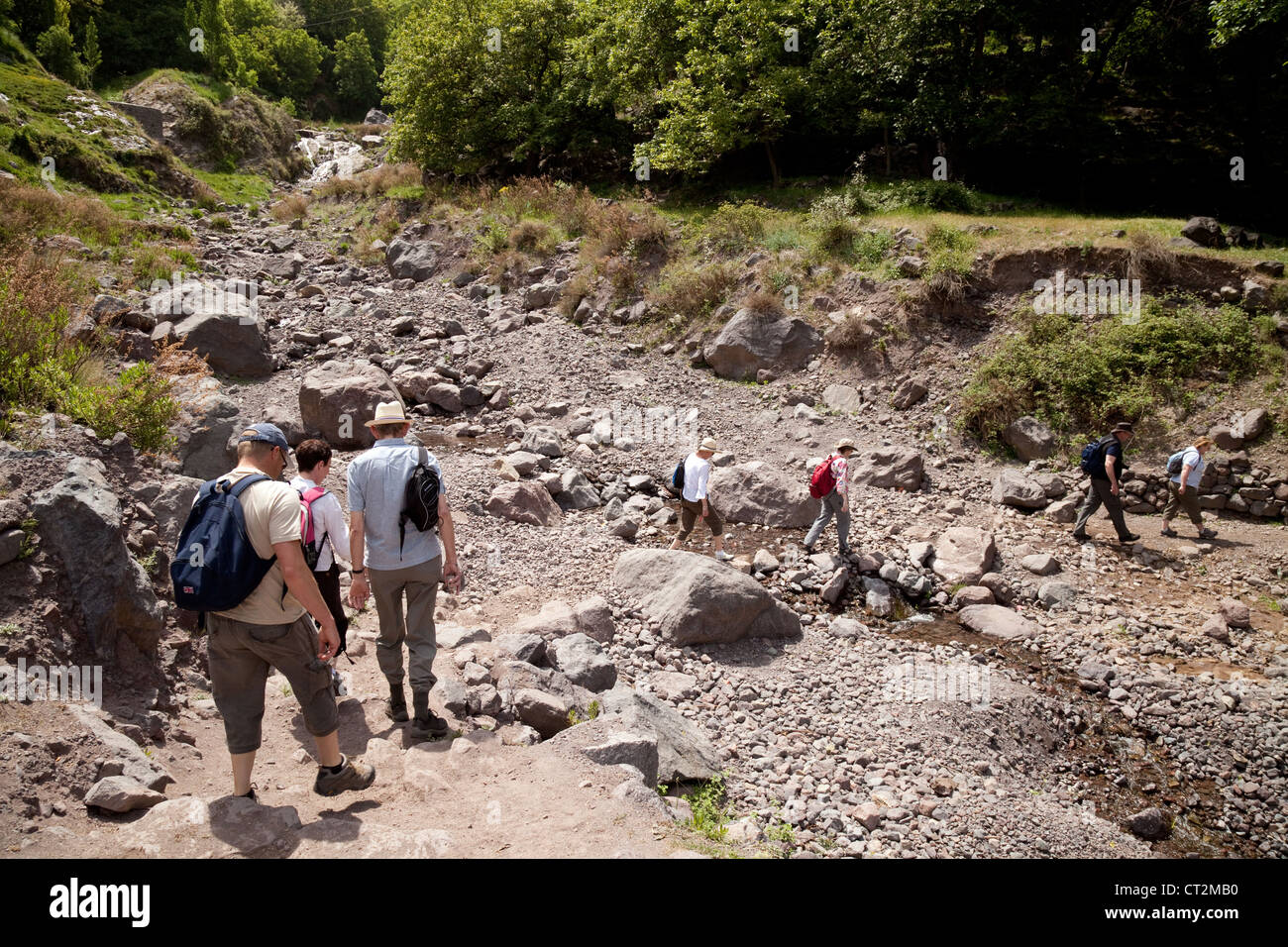 Tourists walking in the HIgh Atlas cross a dried up river bed, near ...