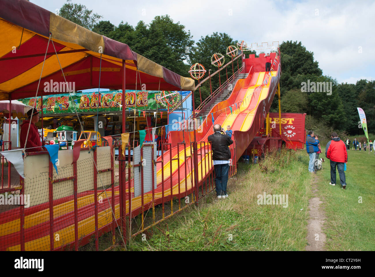 Man taking photograph at bottom of slide while child is held at the top ...