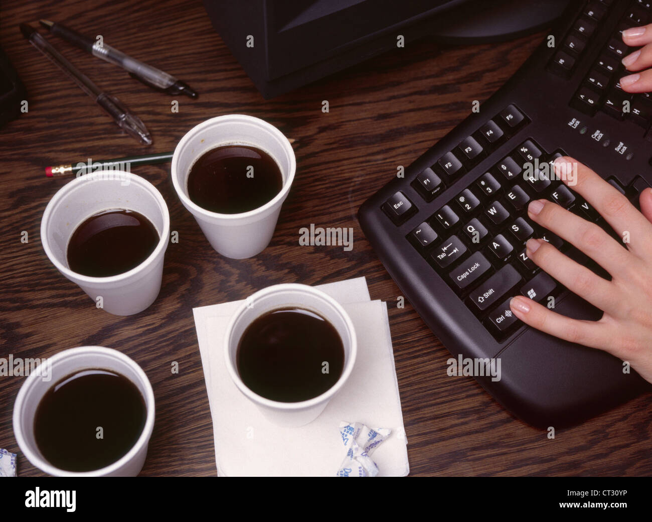 A person typing on a keyboard with several cups of coffee Stock Photo ...